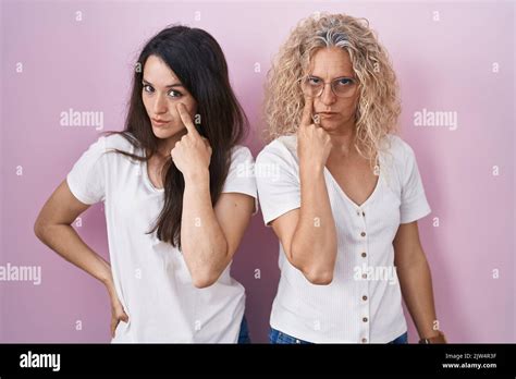 Mother And Daughter Standing Together Over Pink Background Pointing To
