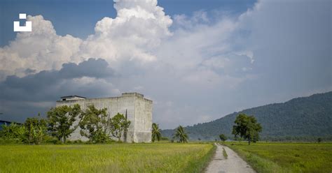 Gray Concrete Building Near Green Grass Field Under White Clouds And