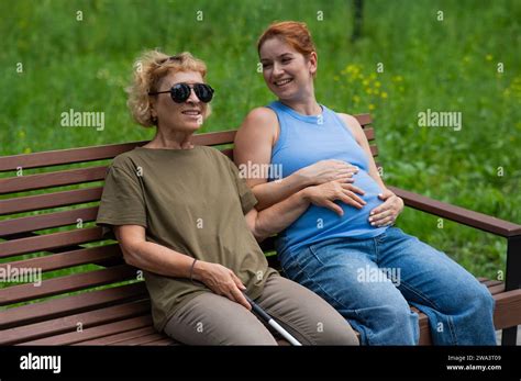 An Elderly Blind Woman Holds Her Pregnant Daughter By The Belly While