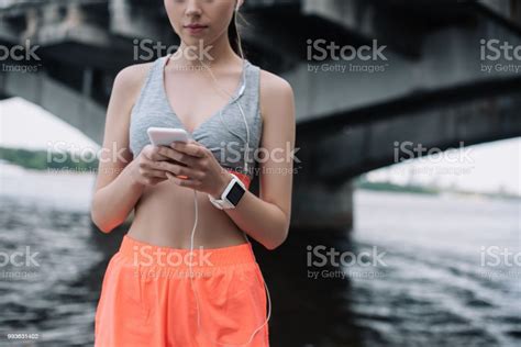 자른 젊은 Sportswoman 이어폰 및 Smartwatch 스마트폰 사용의 보기 강에 대한 스톡 사진 및 기타 이미지 강