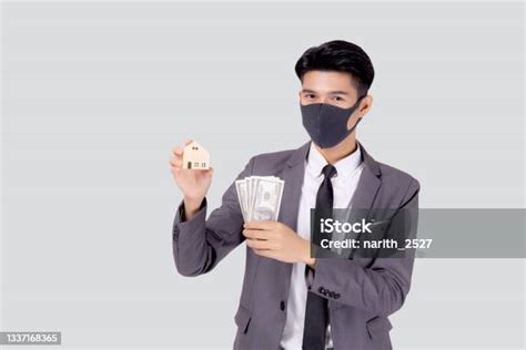 돈 달러와 가정을 들고 얼굴 마스크에 젊은 아시아 사업가 는 질병 Covid19 동안 경제 사업가 및 투자 재산의 흰색 배경