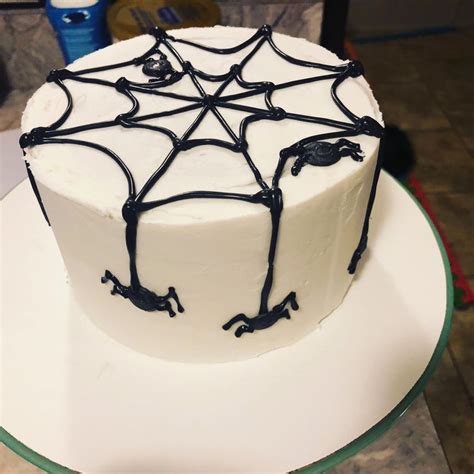 A White Cake Decorated With Black Icing And Spider Web