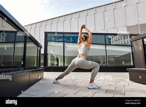 Young Blonde Athlete Doing Exercises Near Modern Urban Building