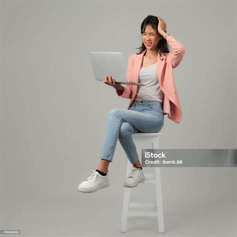 고립된 배경에 의자에 앉아 노트북 컴퓨터를 들고 화난 미친 아시아 여자의 전체 길이 촬영 25 29세에 대한 스톡 사진 및 기타