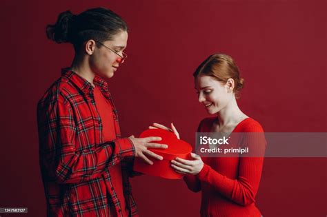 젊은 남자는 빨간 배경 스튜디오에서 발렌타인 데이에 그의 여자 친구에게 하트 모양의 상자를 제공합니다 18 19세에 대한 스톡 사진 및 기타 이미지 Istock