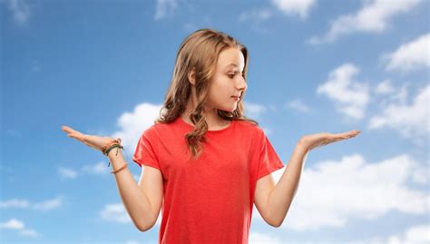 Premium Photo Smiling Teenage Girl Holding Empty Hand Over Sky