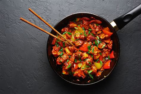 검은 콘크리트 배경에 팬에 치킨 만주 치킨 만주리안은 닭 가슴살 피망 토마토 간장과 인도 중국 요리입니다 복사 공간 0명에 대한