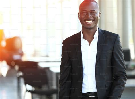 작업 환경에서 카메라를 보고 있는 아프리카계 미국인 비즈니스 리더의 이미지 사진 Unsplash의 전경에 초점 맞추기 이미지