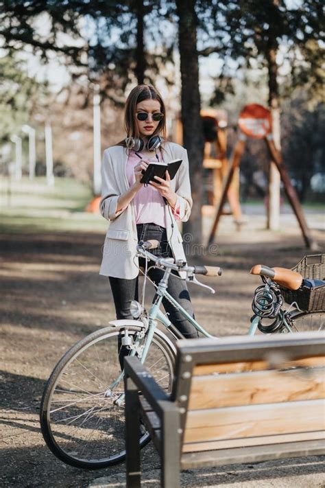 Stylish Young Woman With Bicycle Using Smart Phone In A Park Stock