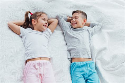 함께 침대에 누워 있는 두 명의 아름다운 형제자매의 탑 뷰 휴식을 취하면서 미소 2명에 대한 스톡 사진 및 기타 이미지 2명