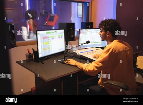 Side View Of Male Audio Engineer Using Mixing Board And Computer Sound