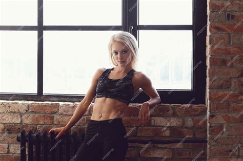 Сексуальная мускулистая спортсменка женщина позирует на окне Бесплатно Фото