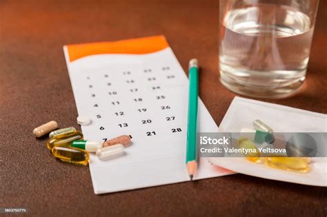 비타민 및 보충제 갈색 배경에 물 한 잔과 달력이 있는 다양한 비타민 정제 매일 복용할 수 있는 종합비타민 영양 보충제 플랫
