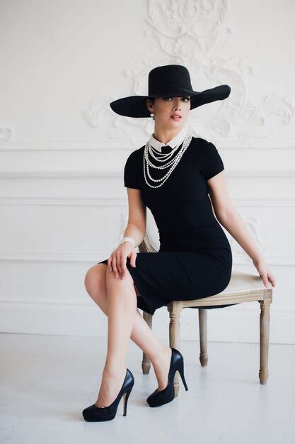 Premium Photo Elegant Woman In Black Dress With A Hat Sitting On Chair