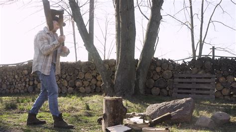 Caucasian Man Chopping Firewood With An Ax Outside A Country House Free