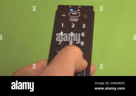 Male Hand Changing Channels With Remote Control On A Green Screen