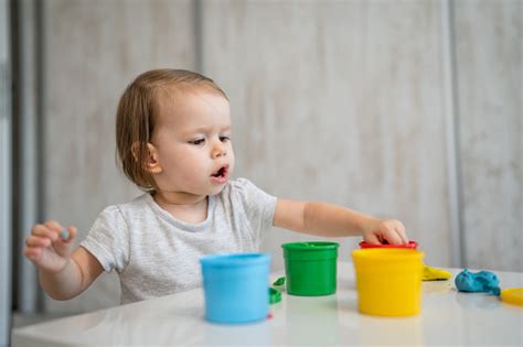 한 소녀 작은 백인 유아 아이가 집에서 혼자 어린 시절에 테이블에 화려한 Plasticine을 가지고 놀고 자라면서 발달 개념 복사 공간 12 17 개월에 대한 스톡 사진