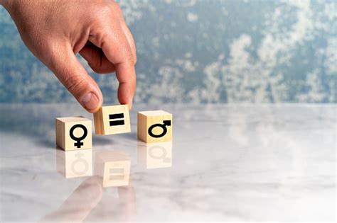 사람은 남성과 여성 기호가 있는 두 개의 나무 큐브 사이에 평등 기호를 배치합니다 Equal Pay Day에 대한 스톡 사진 및