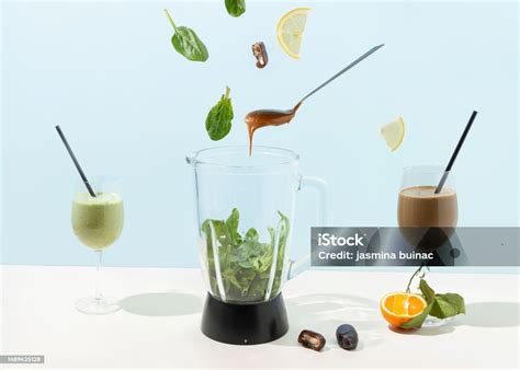 스무디 만들기 떠 있는 시금치 잎 레몬 땅콩 버터 대추야자 오렌지가 고립된 파스텔 블루 배경에 있다 항산화제인 루테인 케르세틴