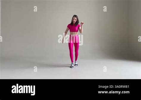 Woman Performing Salsa In A Vibrant Pink Costume Against A Neutral Gray