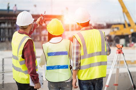Civil Engineers At Construction Site And A Land Surveyor Using An
