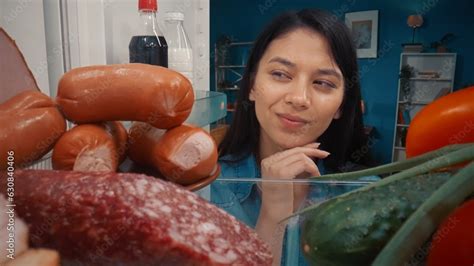 An Asian Woman Stands At An Open Refrigerator With Healthy And