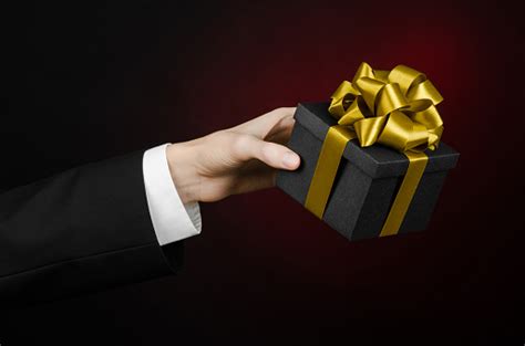 축 하와 선물의 테마 절연 스튜디오에 어두운 빨간색 배경에 골드 리본 아름 다운 블랙 박스에 포장 하는 독점적인 선물 비싼