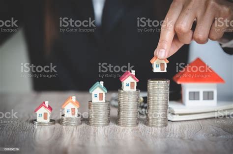 동전 스택에 집 모델을 넣어 여자의 손 부동산 사다리에 대한 개념 주택에 대한 주택 개념 부동산 모기지 및 투자를 구입하는