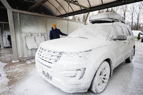 추운 날씨에 셀프 서비스 세차장에서 지붕 선반이 있는 미국 Suv 차를 세차하는 남자 프리미엄 사진