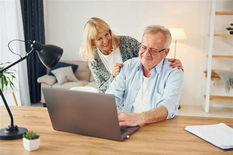 Usando una computadora portátil el hombre y la mujer mayores están juntos en casa Foto Premium