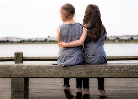 Premium Photo Full Length Rear View Of Girls Sitting On Pier Against
