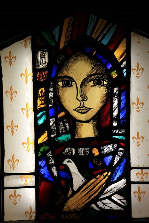 A Stained Glass Window With A Woman Holding A Dove