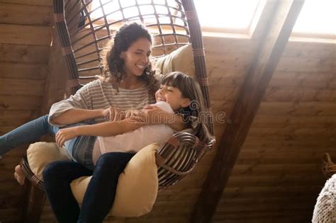 Loving Hispanic Mother Sit In Chair Swing Tickle Little Daughter Stock