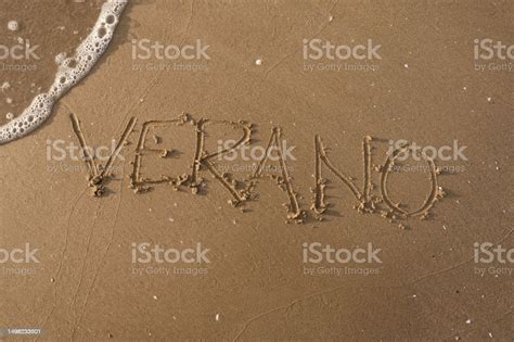 여름은 젖은 해변 모래사장에 스페인어로 손으로 쓴 것으로 왼쪽에는 바다 거품이 있는 오버헤드 전망이 있습니다 0명에 대한 스톡