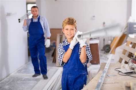 파란색 작업복을 입은 소년은 방을 개조하기 위해 어깨에 알루미늄 프로파일을 가지고 있습니다 2명에 대한 스톡 사진 및 기타 이미지 Istock