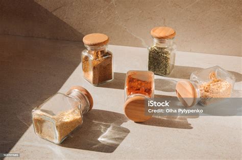 그림자가있는 밝은 돌 배경에 유리 항아리에있는 조미료 그룹 파프리카 허브 겨자 마늘 정면 전망 유리 재료에 대한 스톡 사진 및
