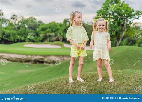Two Adorable Sisters Share A Heartwarming Moment On A Green Lawn Their