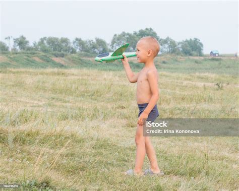 반바지에 귀여운 어린 소년은 필드를 가로 질러 걸어 그의 손에 장난감 비행기를 들고있다 4 5세에 대한 스톡 사진 및 기타