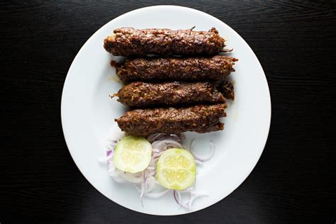 쇠고기 Seekh Kabab와 오이와 양파 샐러드는 인도 향신료 방글라데시 및 파키스탄 음식의 접시 고립 된 어두운 배경