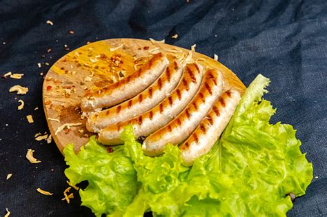 붉은 색과 흰색 생선 고기에서 튀긴 수제 핫도그 소시지 빈티지 소박한 접시 그릇 포크 나이프 숟가락 향신료 허브 스탠드 와 거짓말 각도 나무 도마에 어두운 빛 건강한