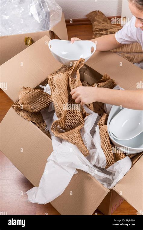 Detail Of Woman Packaging Fragile Items Using Crumpled Packing Paper Concept Of Moving In Or