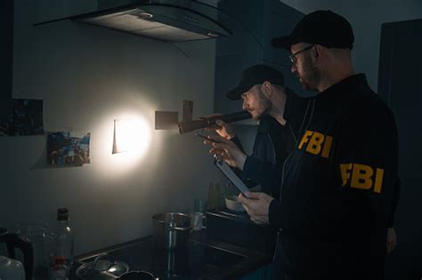 제복을 입은 두 명의 Fbi 요원이 범죄자 소굴의 어두운 방에서 범죄 현장을 검사합니다 범인에 대한 스톡 사진 및 기타 이미지