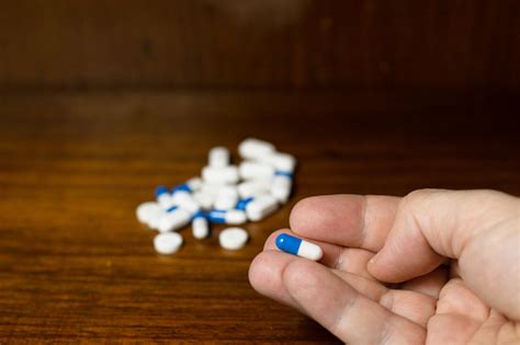 白のシンプルな山 青と黄色の丸薬 薬 茶色の背景に積み重ねられた丸薬 1人のストックフォトや画像を多数ご用意 1人 カラー画像