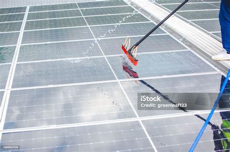 전문 노동자가 브러시로 태양 전지판을 청소하고 건물 공장의 지붕 구조에 물을 씻습니다 걸레를 사용하여 더러움과 먼지를 청소하는 기술자 녹색 전기 에너지 기술 씻기에 대한