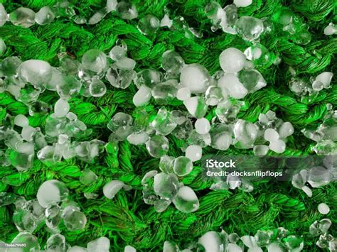 Small Frozen Pellets Of Hail Set Against A Vibrant Green Background