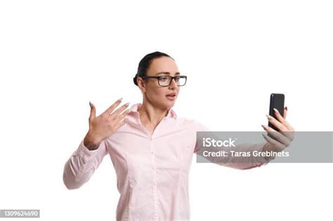 젊은 매력적인 갈색 머리 에 핑크 셔츠 와 팔의 길이에 휴대 전화를 들고 흰색 배경에서 격리된 공간을 복사합니다