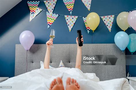 팔을 들고 침대에 누워 샴페인 한 잔과 Tv 리모컨을 들고 누워있는 여성 패시브 생일 계획 너 자신을위한 시간 집에서 휴가 생일