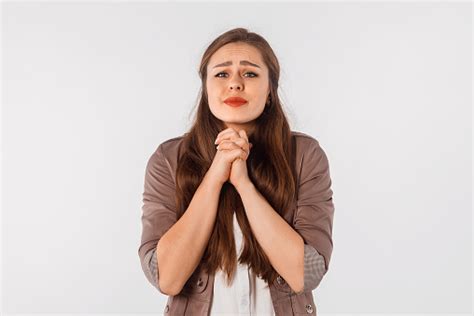 희망에 찬 젊은 여자가 주먹을 꽉 쥐고 꿈을 구하는 소원을 빌고 있다 갈색 머리 소녀는 무언가를 원하거나 행운을 빌거나 무언가를