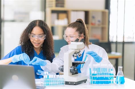 두 명의 여성 과학자가 현대식 실험실의 시험관에서 액체를 검사하고 특수 보호복을 입은 채 화학 물질과 실험 물질을 정밀하게 취급합니다 2명에 대한 스톡 사진 및 기타 이미지