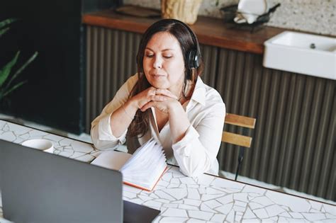Premium Photo Adult Smiling Brunette Woman In Headphones Doing Notes In Daily Book With Opened